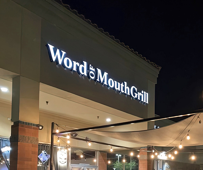 The illuminated sign of Word of Mouth Grill beckons hungry patrons like a barbecue lighthouse guiding meat-lovers safely to shore.
