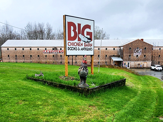 The imposing stone facade of Big Chicken Barn welcomes visitors with its iconic red sign and whimsical rooster statue &ndash; a promise of treasures within.