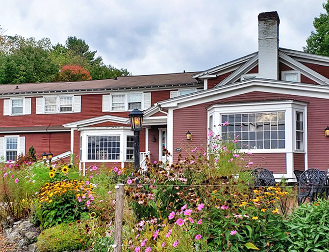 The crimson farmhouse exterior of The Bistro at Ten Acres welcomes guests with vibrant gardens and mountain views&mdash;Vermont hospitality at its finest.