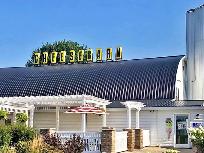 The iconic curved roof topped with bright yellow "CHEESEBARN" letters stands against the blue Ohio sky, beckoning hungry travelers like a dairy-filled lighthouse.