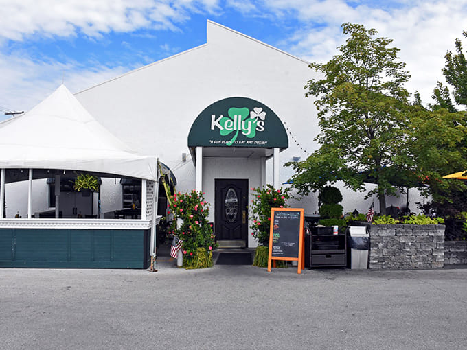 Kelly's welcoming exterior promises Irish charm with its distinctive green shamrock sign and inviting entrance flanked by colorful flowering plants.
