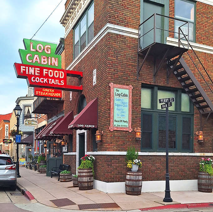 The iconic neon sign of Log Cabin Steakhouse glows against Galena's brick backdrop, promising fine food and cocktails like a delicious lighthouse guiding hungry travelers home.