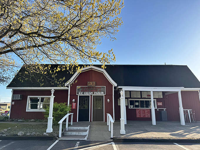 The iconic red barn exterior of Hayloft Ice Cream Parlor stands proudly against Michigan's blue skies, promising sweet treasures within.