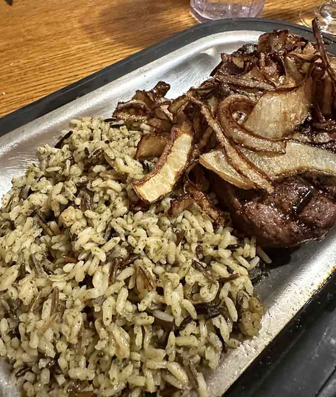 Filet mignon topped with caramelized onions alongside rice, because sometimes you want elegance with your comfort food.