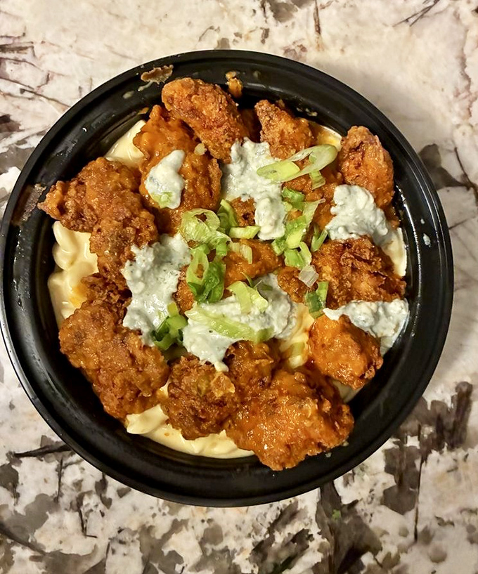 Comfort food elevated to art form &ndash; crispy chicken bites crown a creamy mac and cheese lake, dotted with green onion islands.