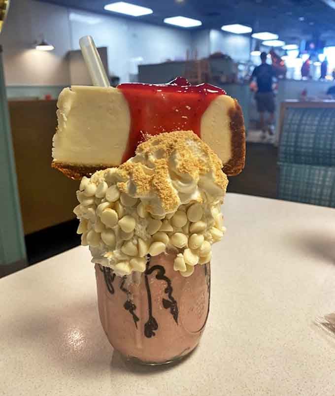This isn't just a milkshake, it's a structural marvel topped with cheesecake that makes you wonder if engineers moonlight in the kitchen.