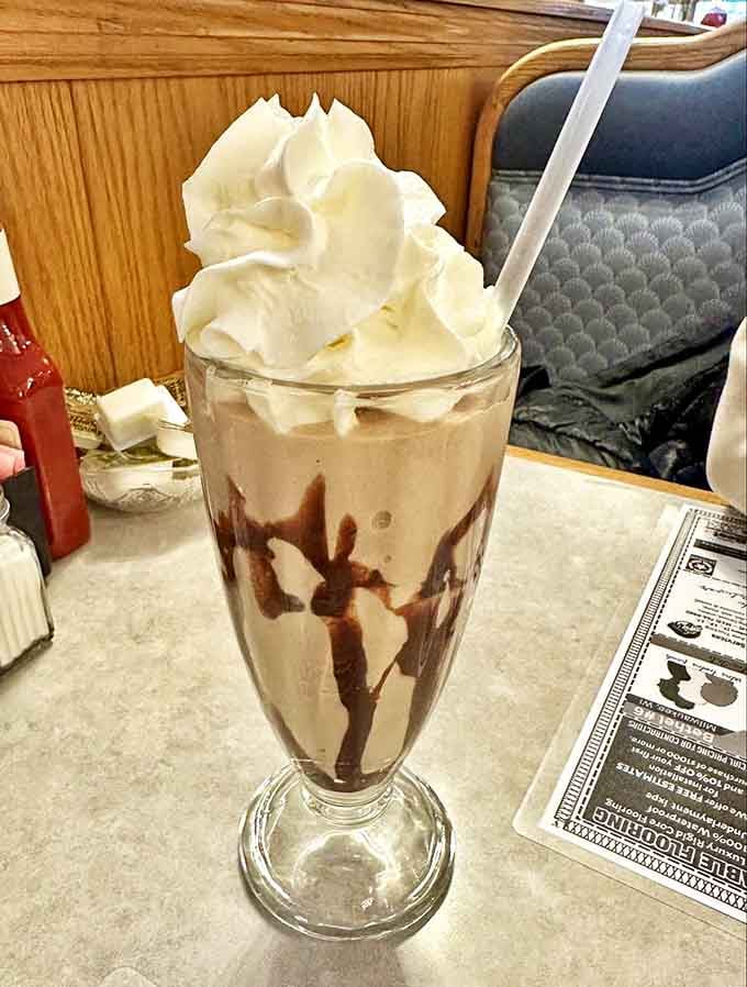 A chocolate milkshake so thick the straw stands at attention, crowned with a cloud of whipped cream &ndash; dessert masquerading as a beverage.