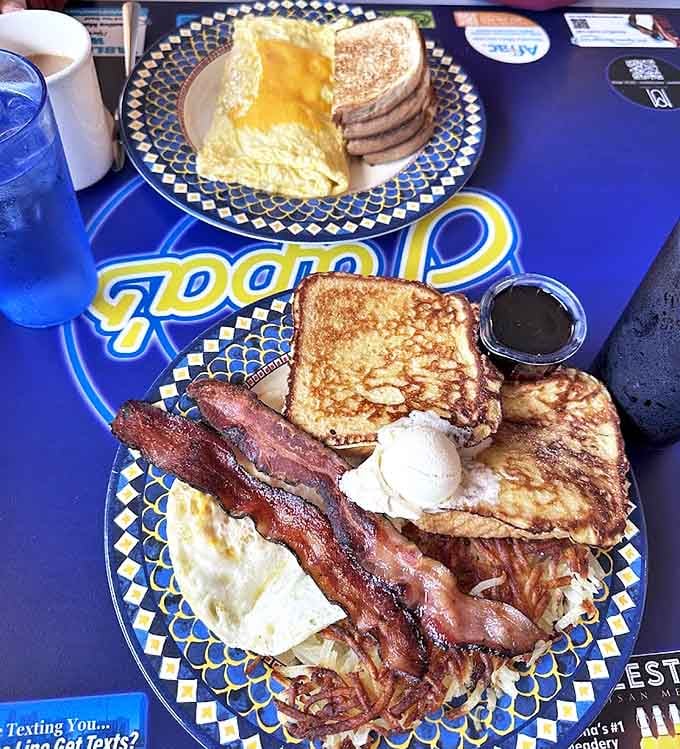 Morning feast featuring perfectly folded omelet alongside crispy hash browns and toast &ndash; breakfast harmony achieved on a blue plate.