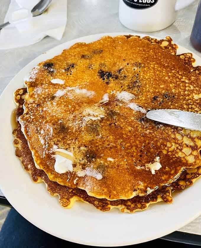 Blueberry pancakes so fluffy they practically float off the plate, dusted with powdered sugar like edible snow.