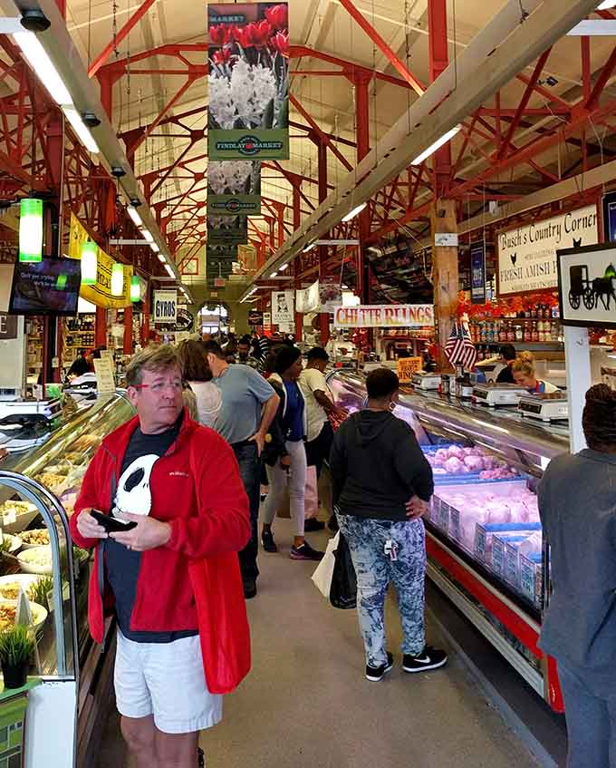 Beneath the market's dramatic red trusses, shoppers navigate a gastronomic wonderland where every aisle promises new flavor adventures.