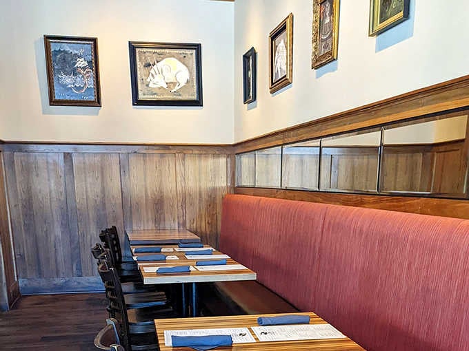 Artwork adorns the walls above comfortable booths, creating an atmosphere that's both refined and relaxed.