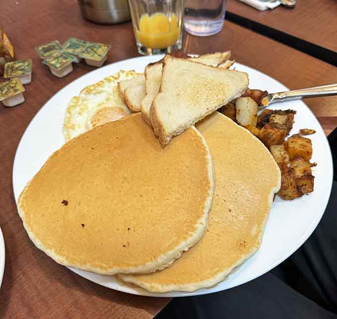 Fluffy pancakes that look like they were made by someone who genuinely cares about your happiness, served with eggs and crispy potatoes.