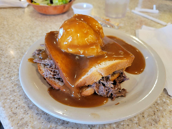 Hot beef sandwich drowning in gravy – the kind of meal that makes you want to hug the chef afterward.
