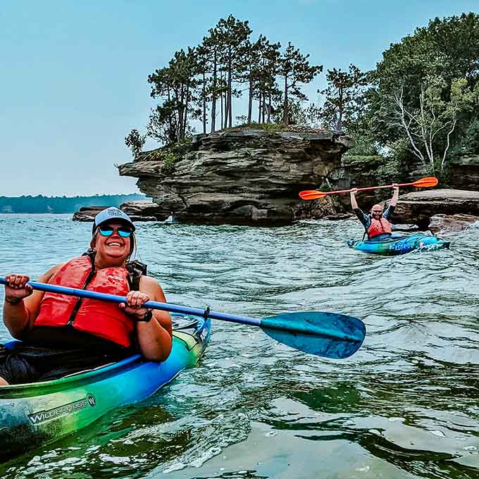 Kayakers navigate through natural stone archways and caves, where Lake Huron's persistent waves have carved windows through solid limestone.
