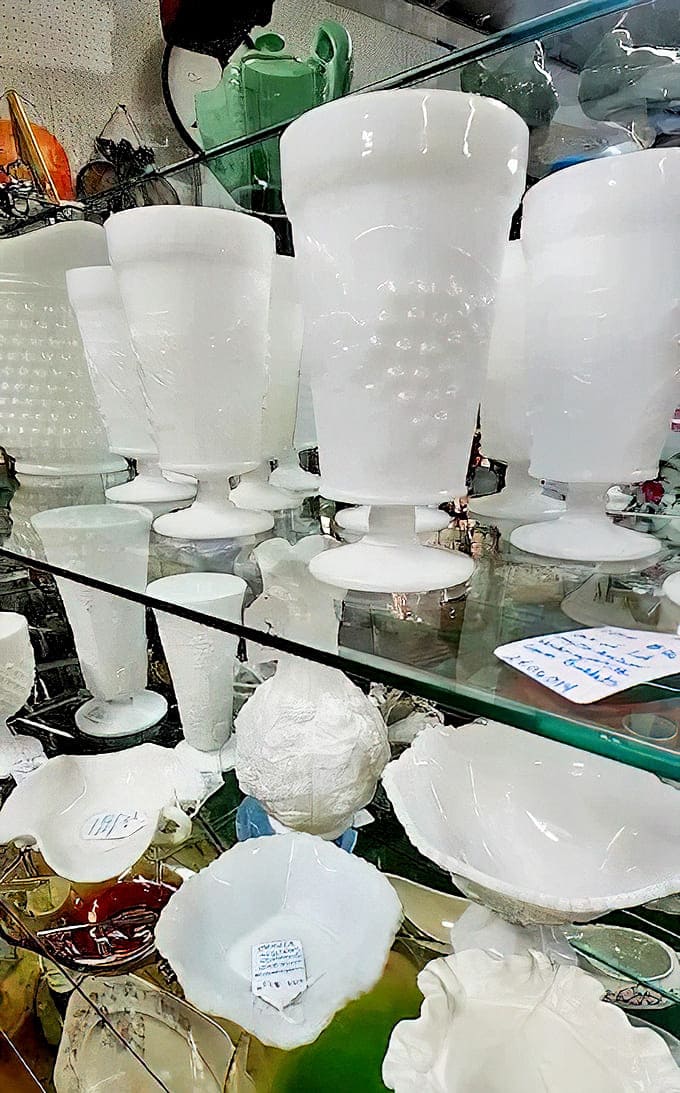 Milk Glass Goblets: Elegant white milk glass goblets stand like ghostly sentinels, their delicate patterns catching light in ways plastic never could.