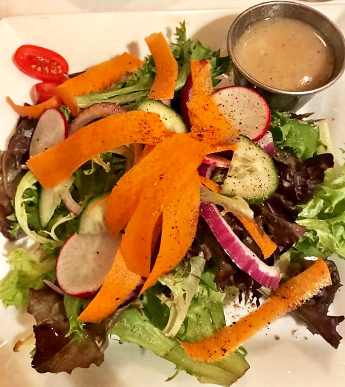 A vibrant mixed greens salad brings color to the table with crisp vegetables and a light champagne vinaigrette that cleanses the palate.