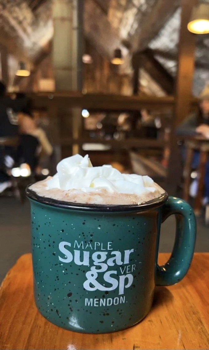 A mug proclaiming "Maple Sugar & Spice" holds a hot beverage topped with whipped cream &ndash; liquid comfort on a cool Vermont morning.