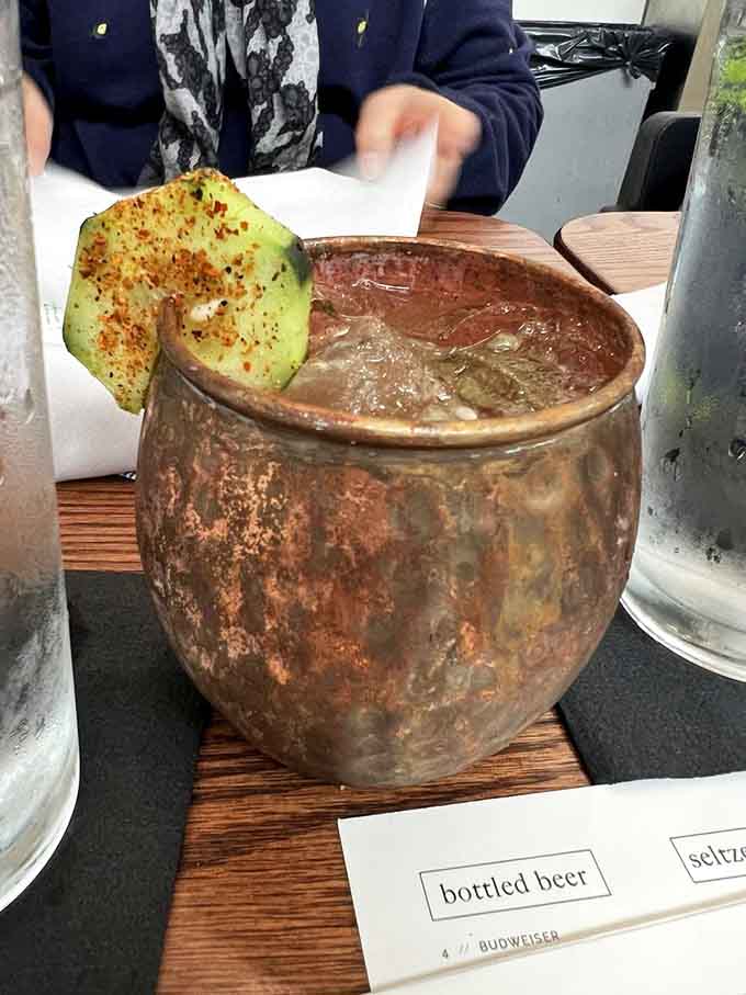 A frothy cocktail with a basil leaf garnish sits pretty on a slate coaster, ready to make your evening significantly more interesting.