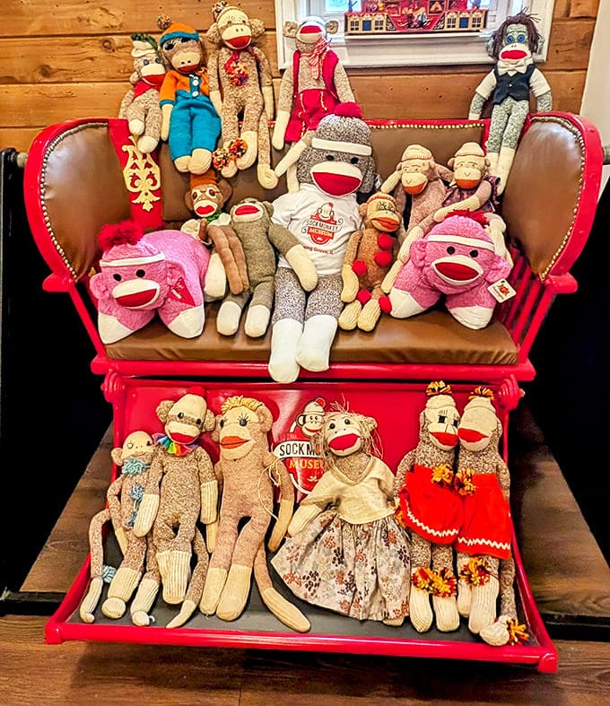 A cozy red couch serves as the perfect perch for a family of sock monkeys, arranged with the care of a formal portrait.