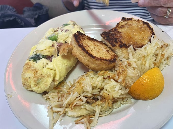 Ham, peppers, and onions tucked into perfectly cooked eggs alongside hash browns that crunch like autumn leaves.