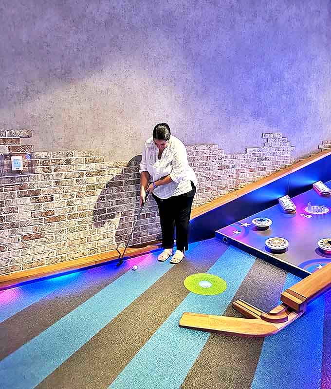 Strategic concentration takes over as this player navigates colorful stripes and challenging obstacles on one of Puttshack's most visually striking holes.