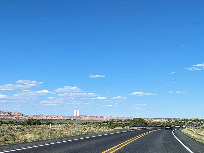 At the highway's edge, civilization fades in the rearview mirror while the dramatic mesas ahead beckon with silent invitation.