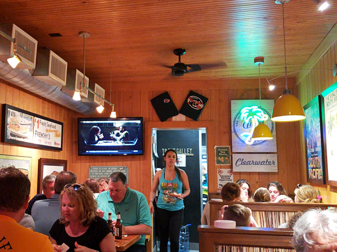 Happy diners sharing stories and seafood in the warm glow of Frenchy's &ndash; where strangers become friends over grouper sandwiches and local fishing tales.