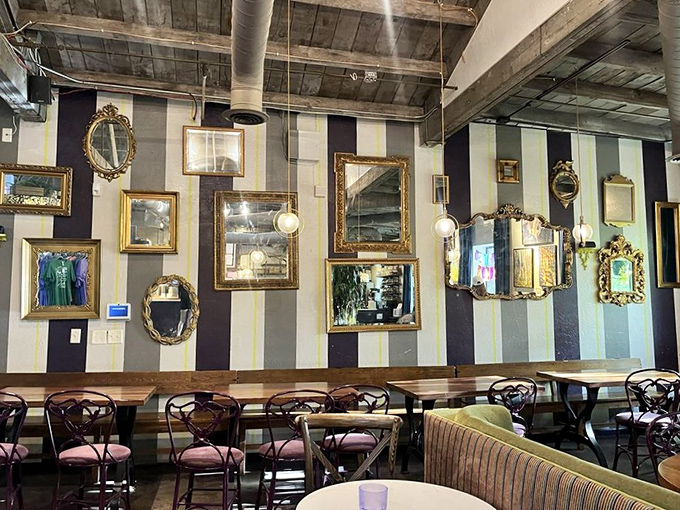 Mismatched mirrors adorn striped walls while wooden tables await the next great conversation &ndash; eclectic perfection in every corner.