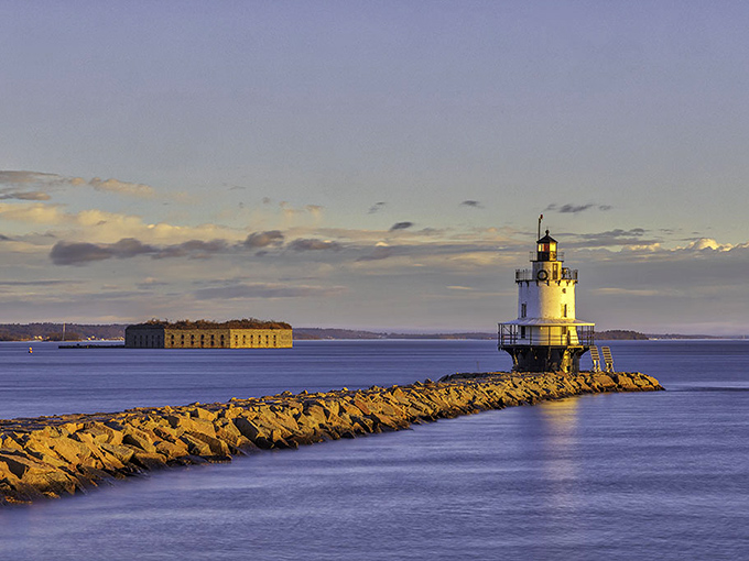 Nature's light show upstages the lighthouse at sunset, painting the sky in dramatic oranges and purples over Casco Bay.