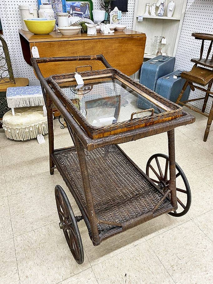The wicker tea cart rolls through time with elegant charm, its wheels having glided across hardwood floors serving refreshments at gatherings long forgotten.