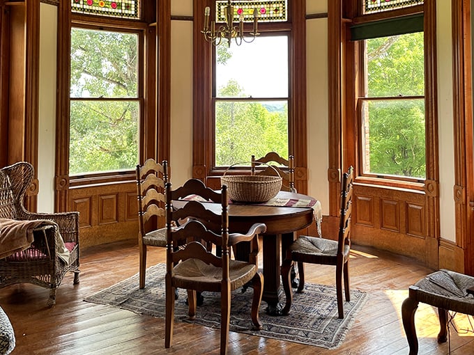 A wooden dining set sits proudly under a vintage chandelier, basket on the table, with sunlight streaming through the grand windows.