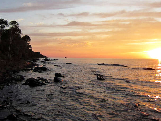 Lake Superior's shoreline erupts in golden light at sunset, transforming the rocky coast into a scene worthy of a national magazine cover.