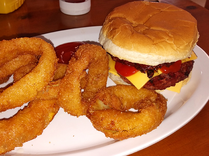 A juicy cheeseburger flanked by golden onion rings &ndash; comfort food elevated through quality ingredients and careful preparation.