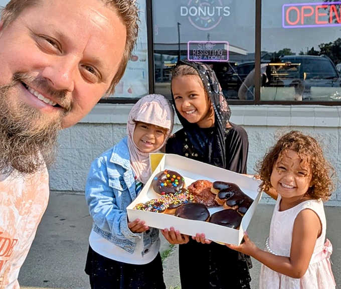 Happy customers showing off their colorful donut treasures&mdash;the universal language of donut joy transcends all ages.