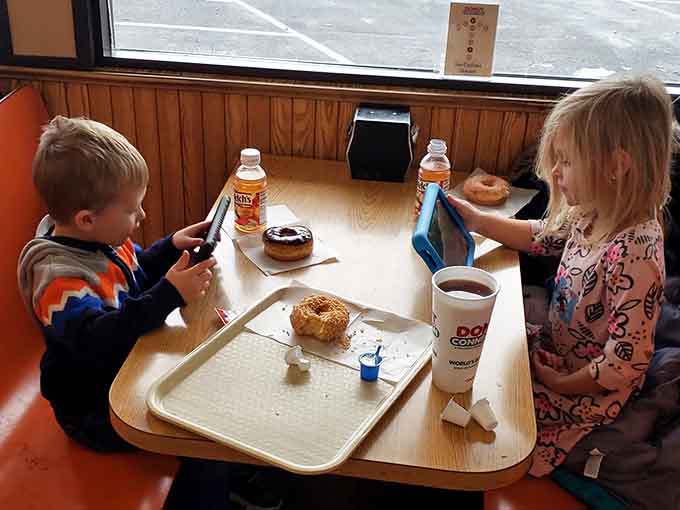 Young breakfast enthusiasts demonstrate that good taste knows no age limit, tackling donuts with admirable focus and determination.