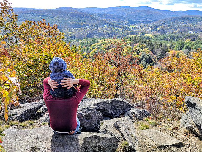 Perched on rocky outcroppings, this visitor takes in the breathtaking panorama of Vermont's rolling hills dressed in autumn's finest colors.