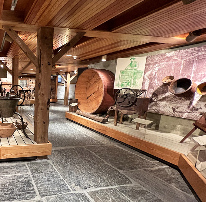 Historic farming equipment on display showcases Vermont's agricultural heritage with wooden barrels and vintage machinery beneath rustic beams.
