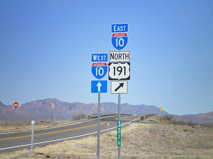 Decision time at the crossroads where Interstate 10 meets Highway 191, each sign promising different adventures across Arizona's varied landscape.