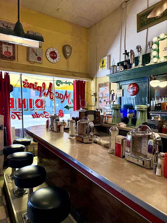 The classic diner counter where conversations flow as freely as the coffee, and strangers become friends over shared pie appreciation.