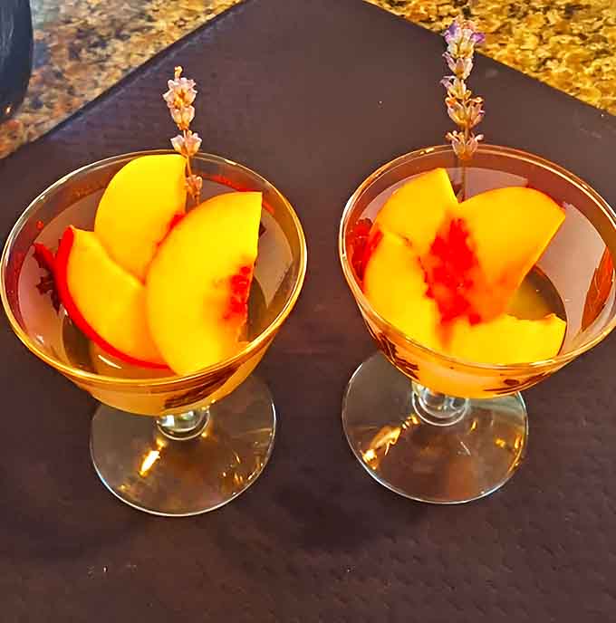 Fresh peach slices and lavender sprigs elevate this simple glass of Muscat into a sensory experience that captures summer in liquid form.