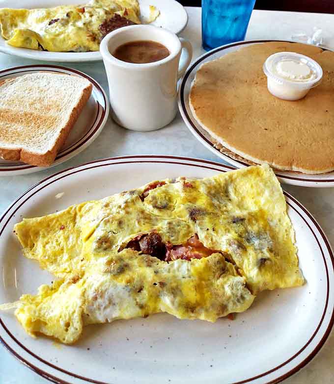 Morning glory on multiple plates: a fluffy omelet that's seen some things, pancakes with ideal syrup-absorption properties, and coffee that means business.