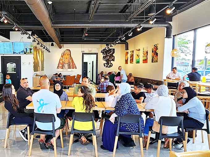 The café buzzes with diverse patrons enjoying conversation and connection – proof that great food and drink create community across all backgrounds.