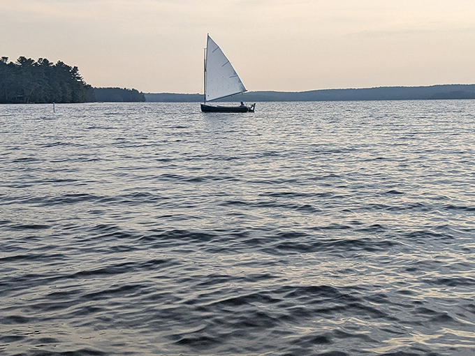 A lone sailboat catches the evening breeze, painting a postcard-perfect scene on Damariscotta's liquid canvas.