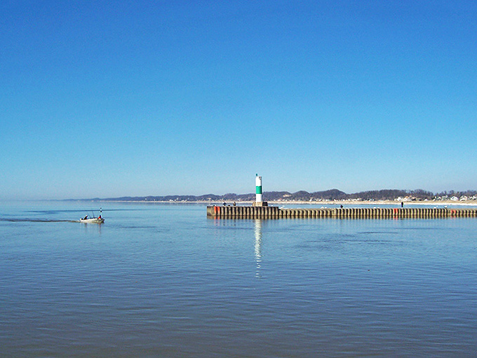 Morning light creates a perfect mirror image of the lighthouse on Lake Michigan's surface, doubling the visual delight.