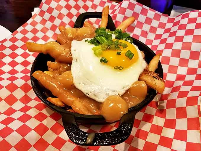 Poutine elevated to art form – golden fries swimming in savory gravy, topped with a perfectly fried egg that's just begging to be broken.