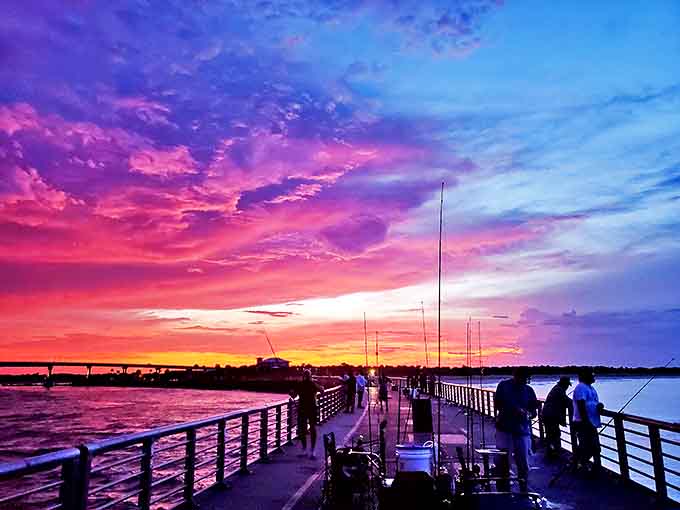 Sunset transforms the sky into a painter's palette, while silhouetted figures along the pier witness nature's nightly masterpiece.