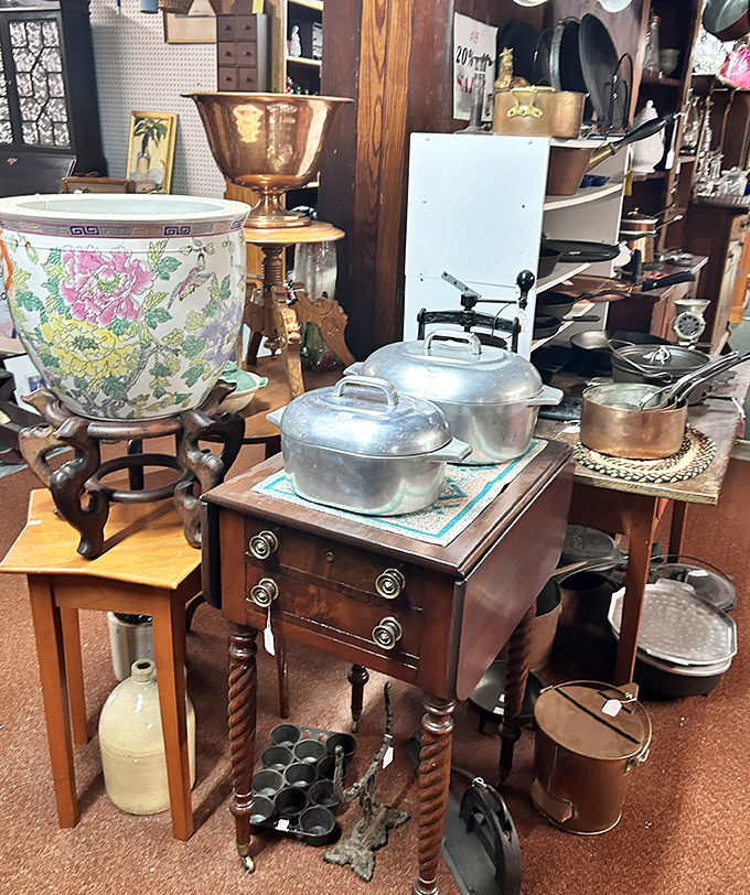 Copper and cast iron cookware displayed on an antique sewing table &ndash; kitchen tools that have outlived several generations of family cooks.
