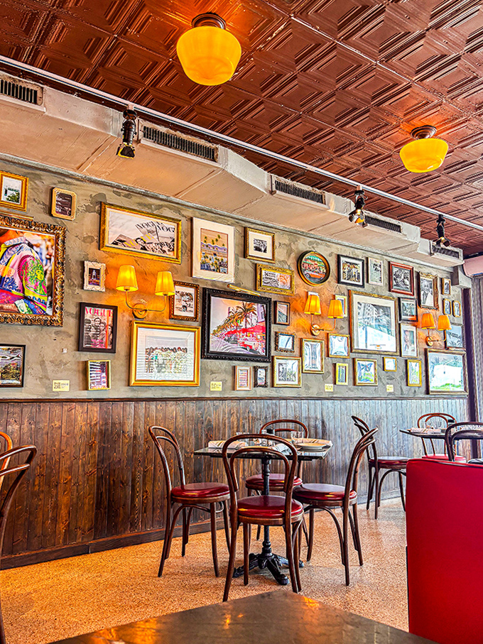 The wall gallery transforms dining into a cultural experience, where vintage frames hold pieces of Miami Beach history, illuminated by the warm glow of amber lamps.