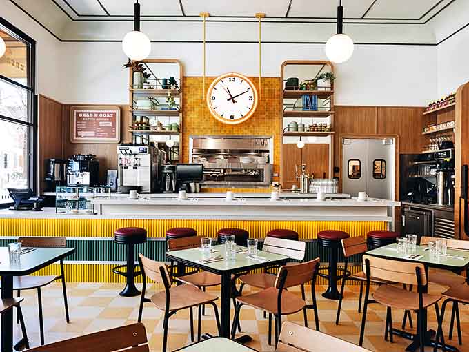 Behind the cheerful yellow-accented counter, staff prepare to deliver Little Goat's signature blend of hospitality and culinary creativity.