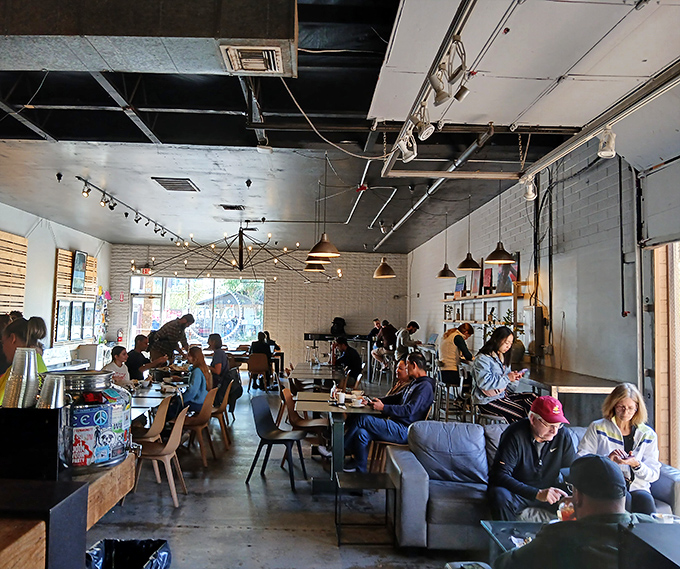 Industrial elements like exposed ceiling beams create an urban loft vibe softened by natural light and wooden accents.